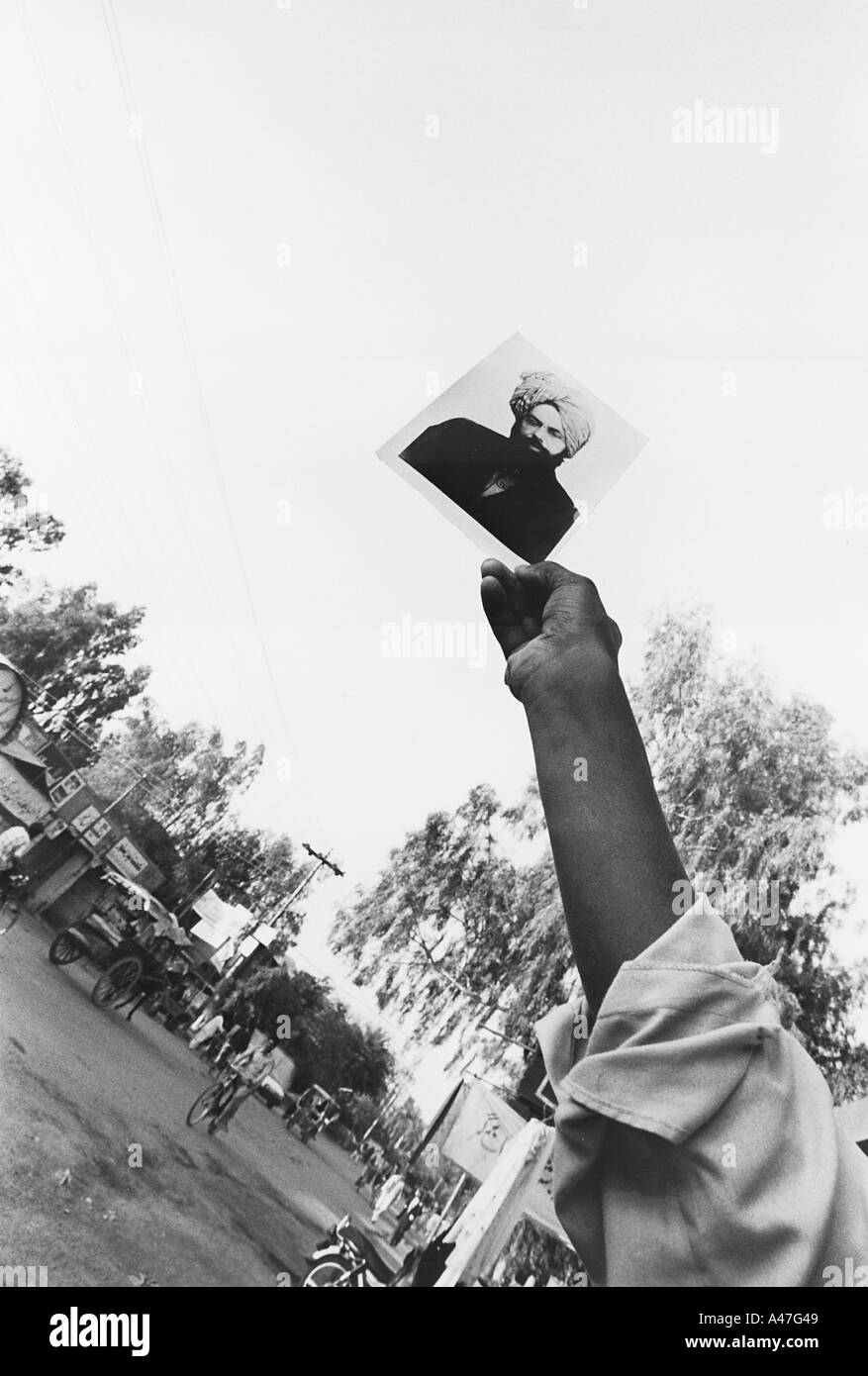 a man holds aloft a portrait of Hazrat Mirza Ghulam Ahmad the founder ...
