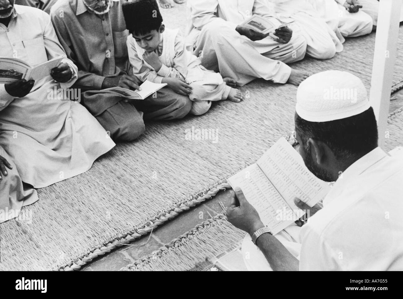 an old ahmadiya man teaches a child a passage from a religious text ...