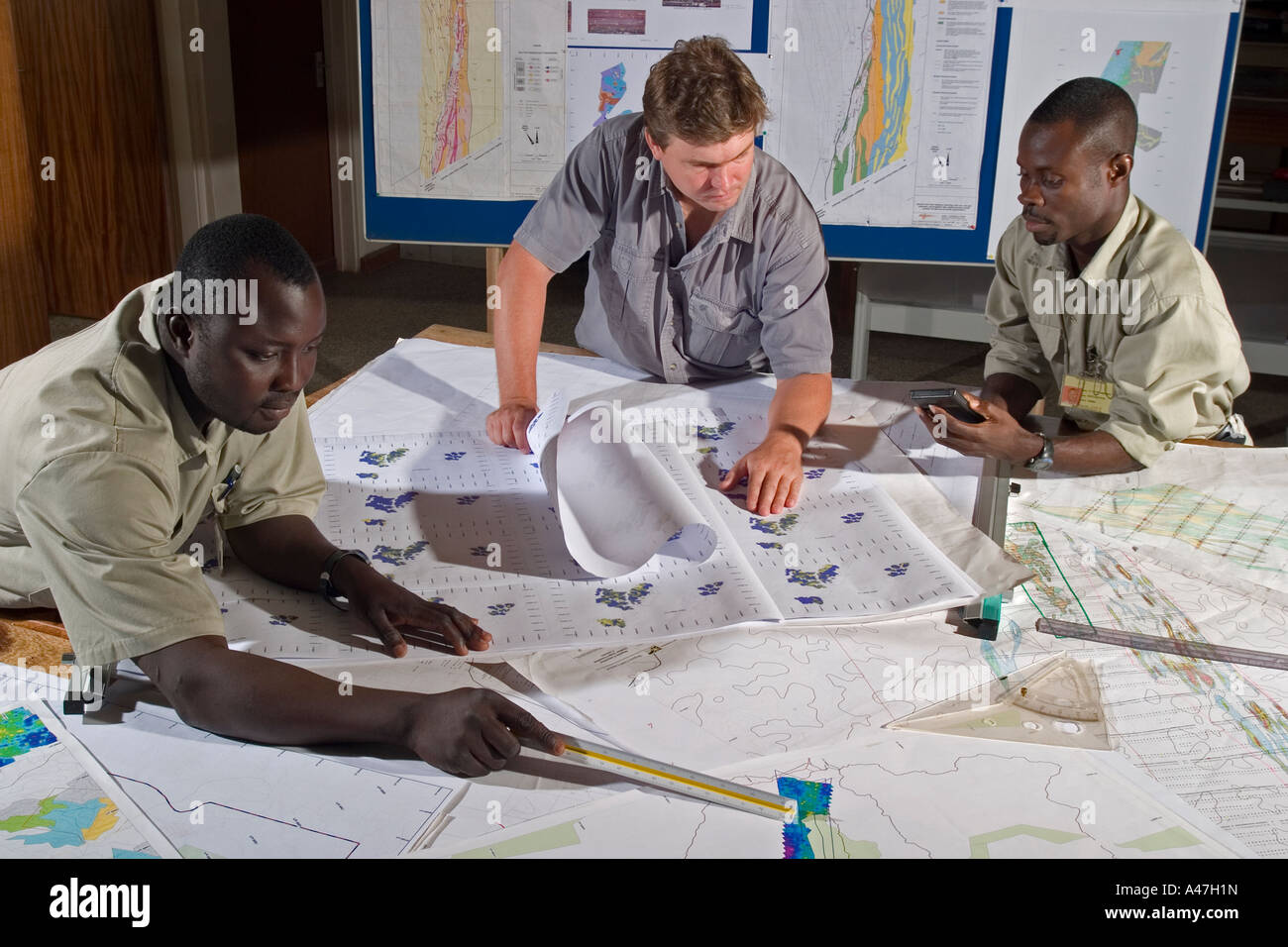 Geologists examining maps and discussing exploration targets, geology ...