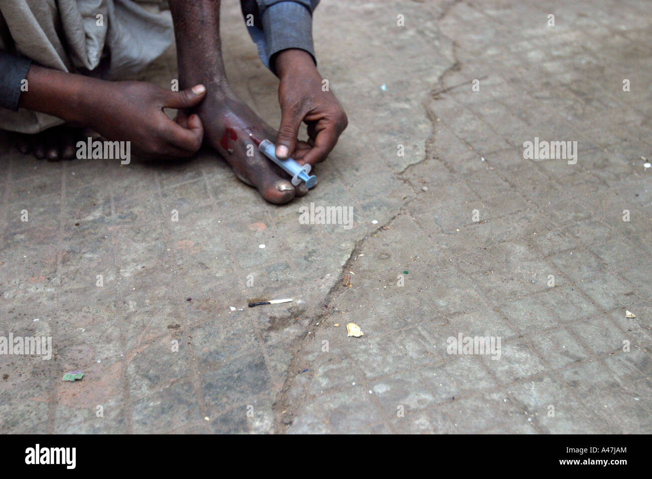 A homeless drug addict injects heroin on a New Delhi street in India ...