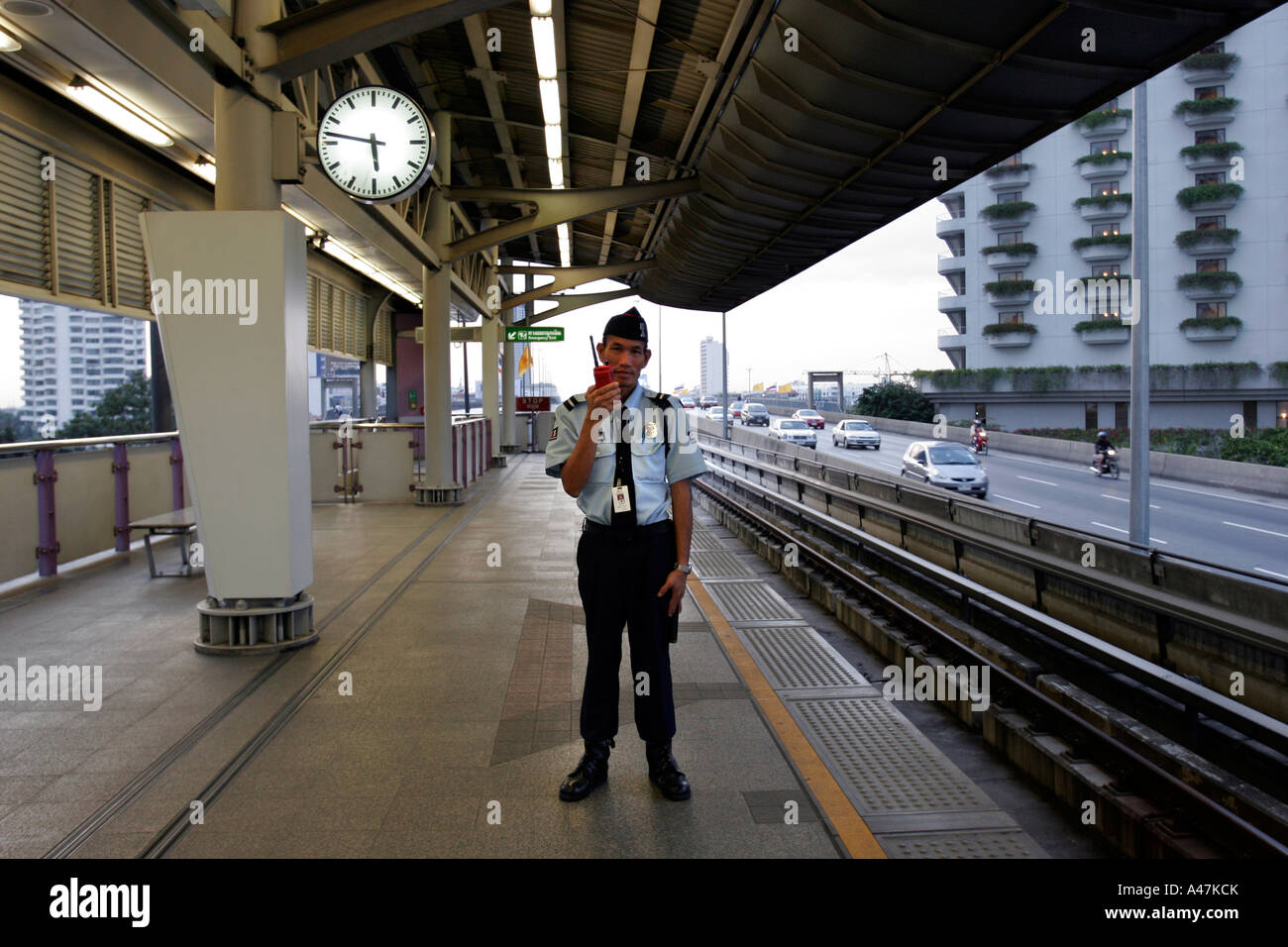 A security guard stands on a platform at a local train station in ...