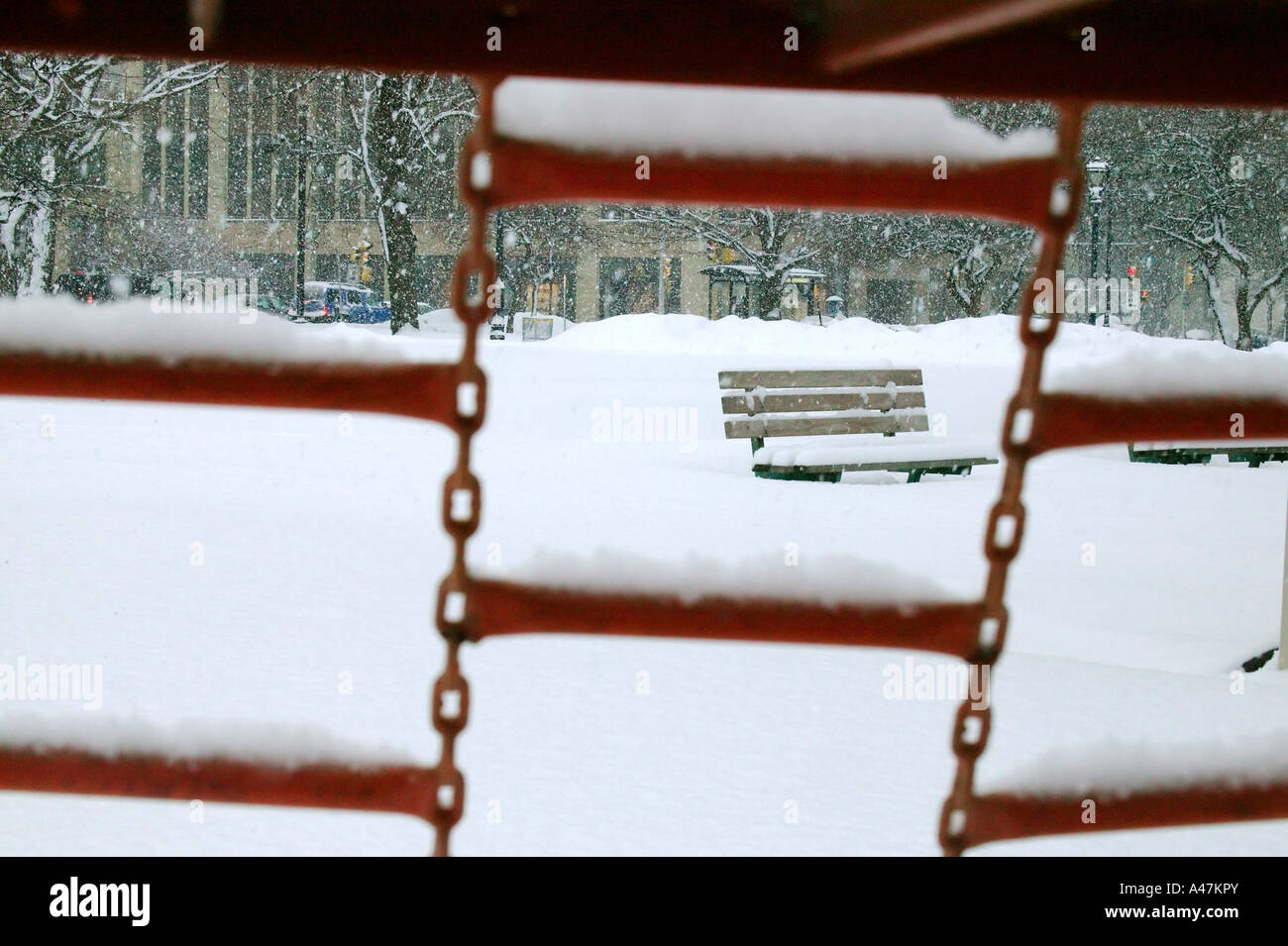 Park bench in the snow seen through play structure steps Stock Photo ...