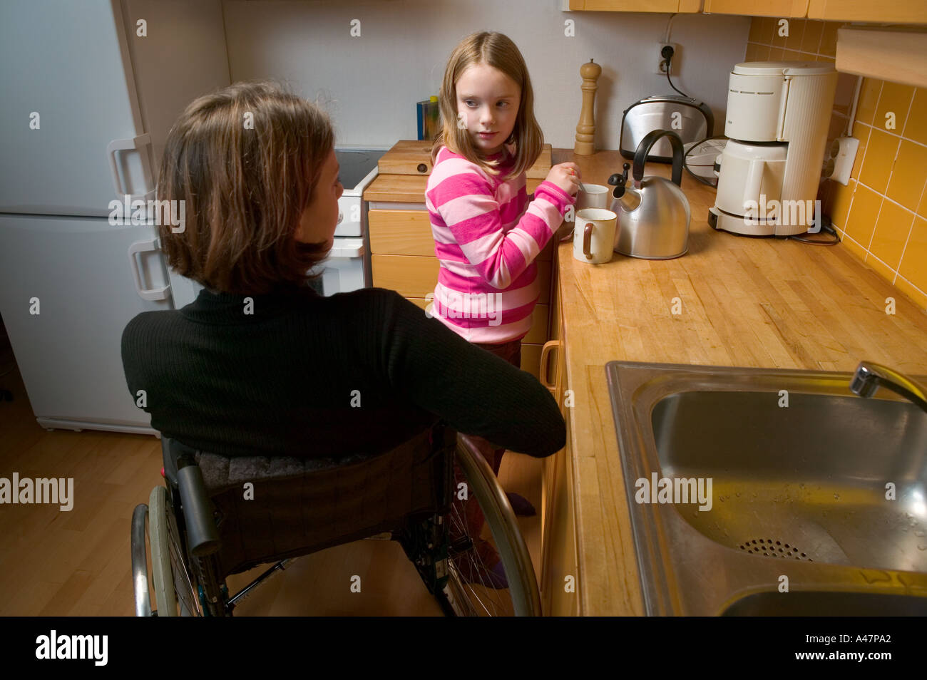 Disabled mother and daughter in kitchen Stock Photo - Alamy