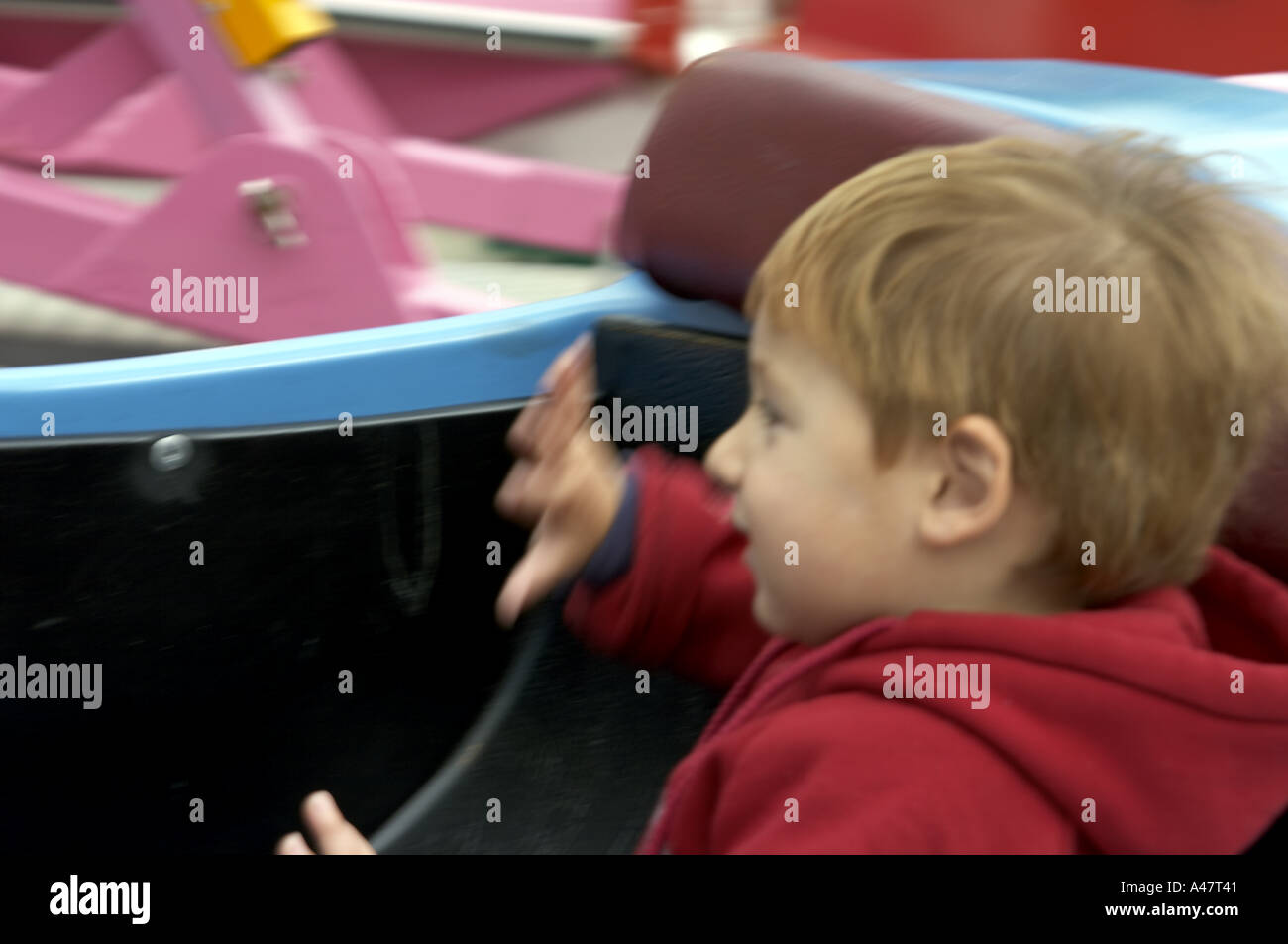Young boy waving on fairground ride Stock Photo - Alamy