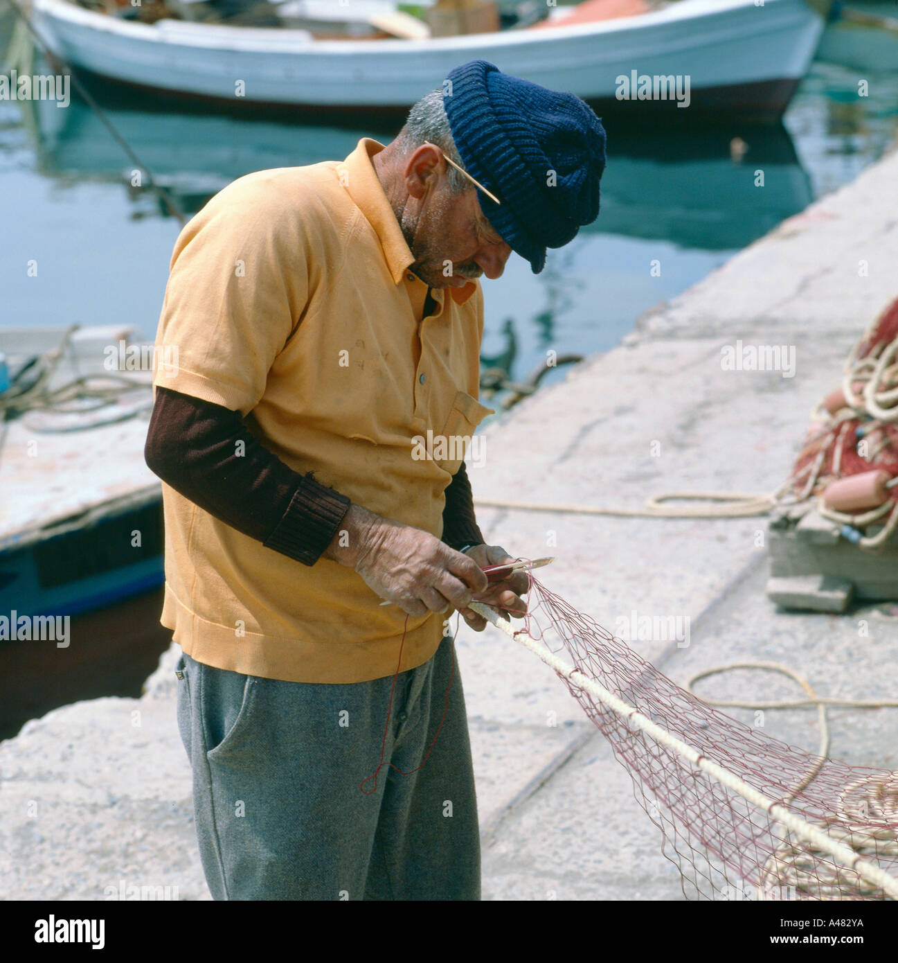 Fisherman repairing net Stock Photo - Alamy