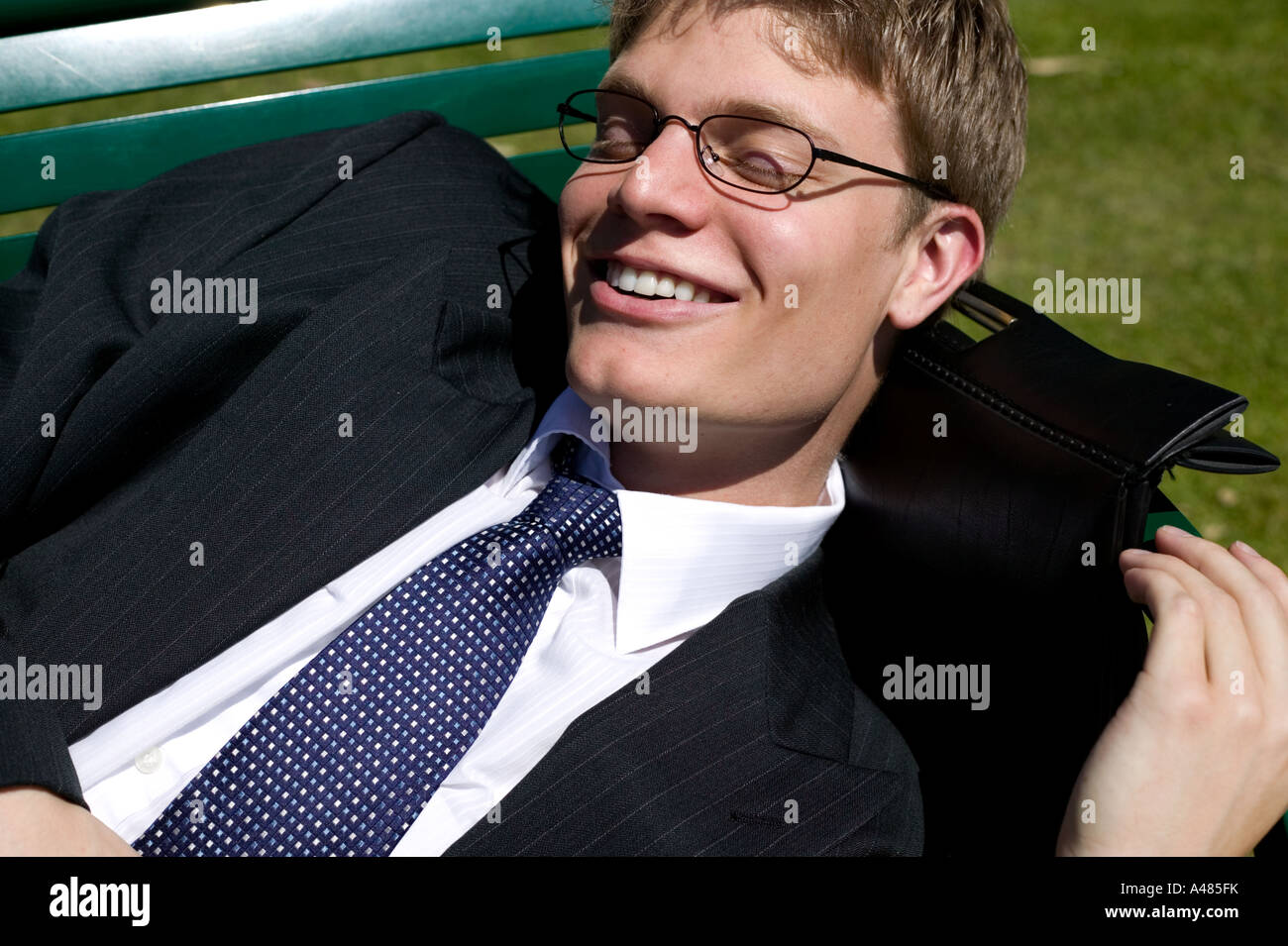 Young man relaxing on bench, smiling Stock Photo - Alamy