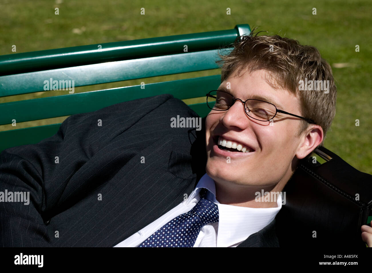 Young man relaxing on bench, smiling Stock Photo - Alamy