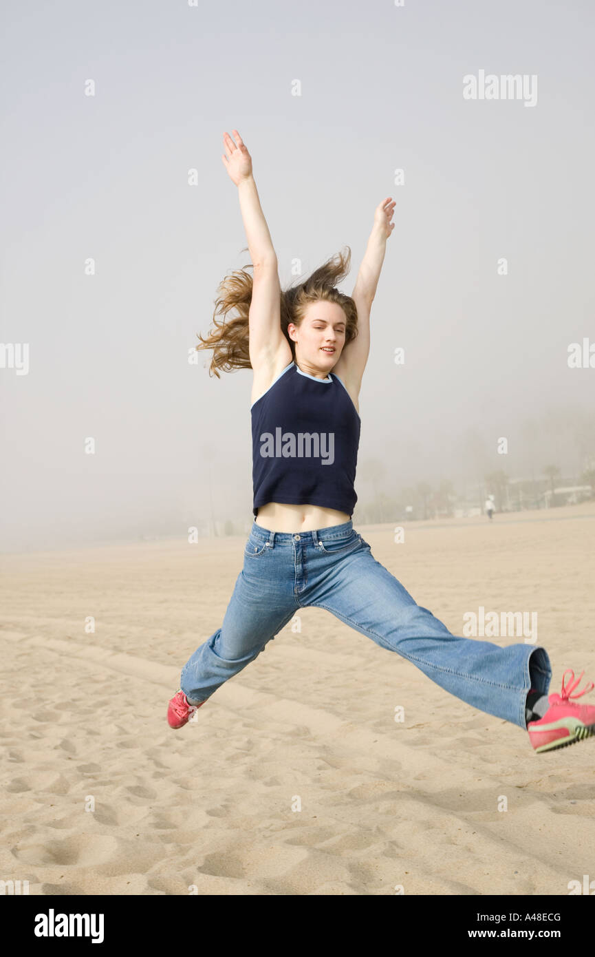 Young woman jumping with arms raised Stock Photo - Alamy