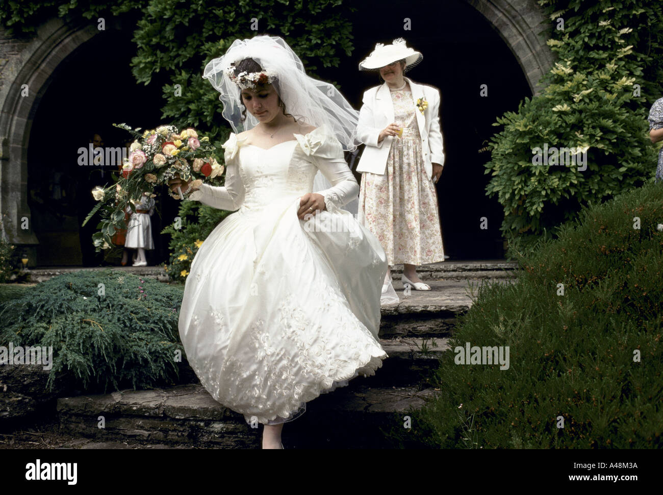 bride running down steps watched by her mother at wedding reception ...