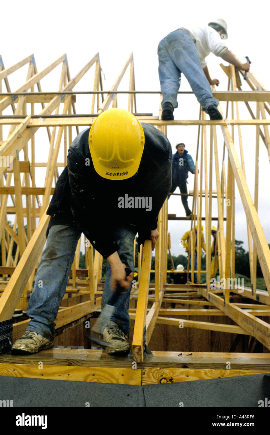 workers hammering timber on roof structure under rain hard hat Stock ...