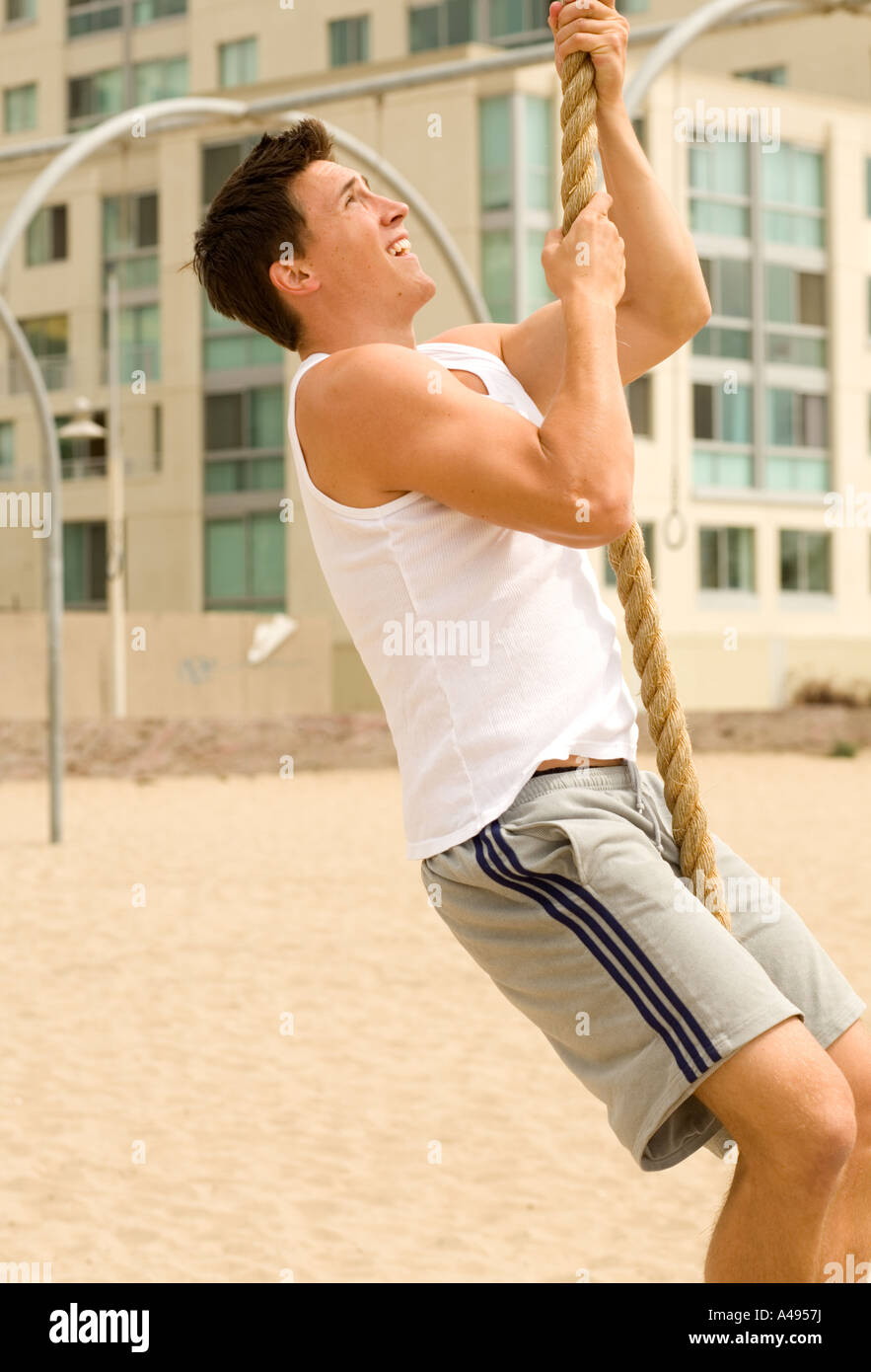 Young man climbing rope Stock Photo - Alamy