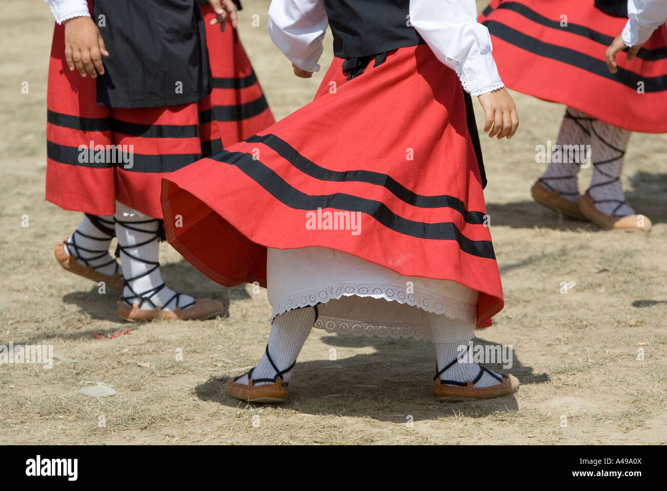 Traditional red dresses worn by female Basque folk dancers swirling as ...