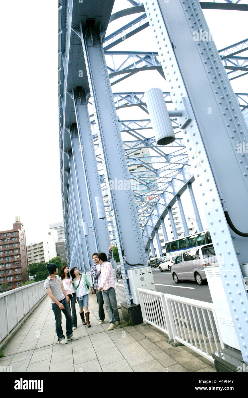 Three young men and two young women walking on a bridge Stock Photo - Alamy