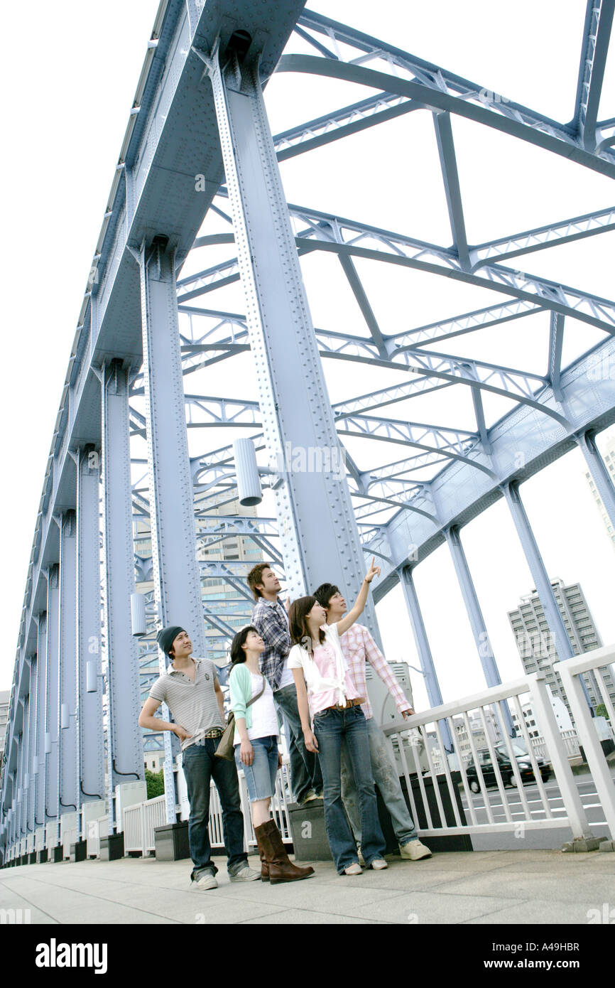 Three young men with two young women standing on a bridge and looking ...