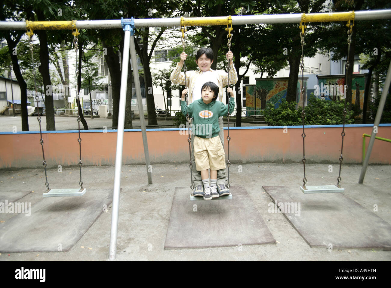 Mid adult man and his son sitting on a swing Stock Photo - Alamy