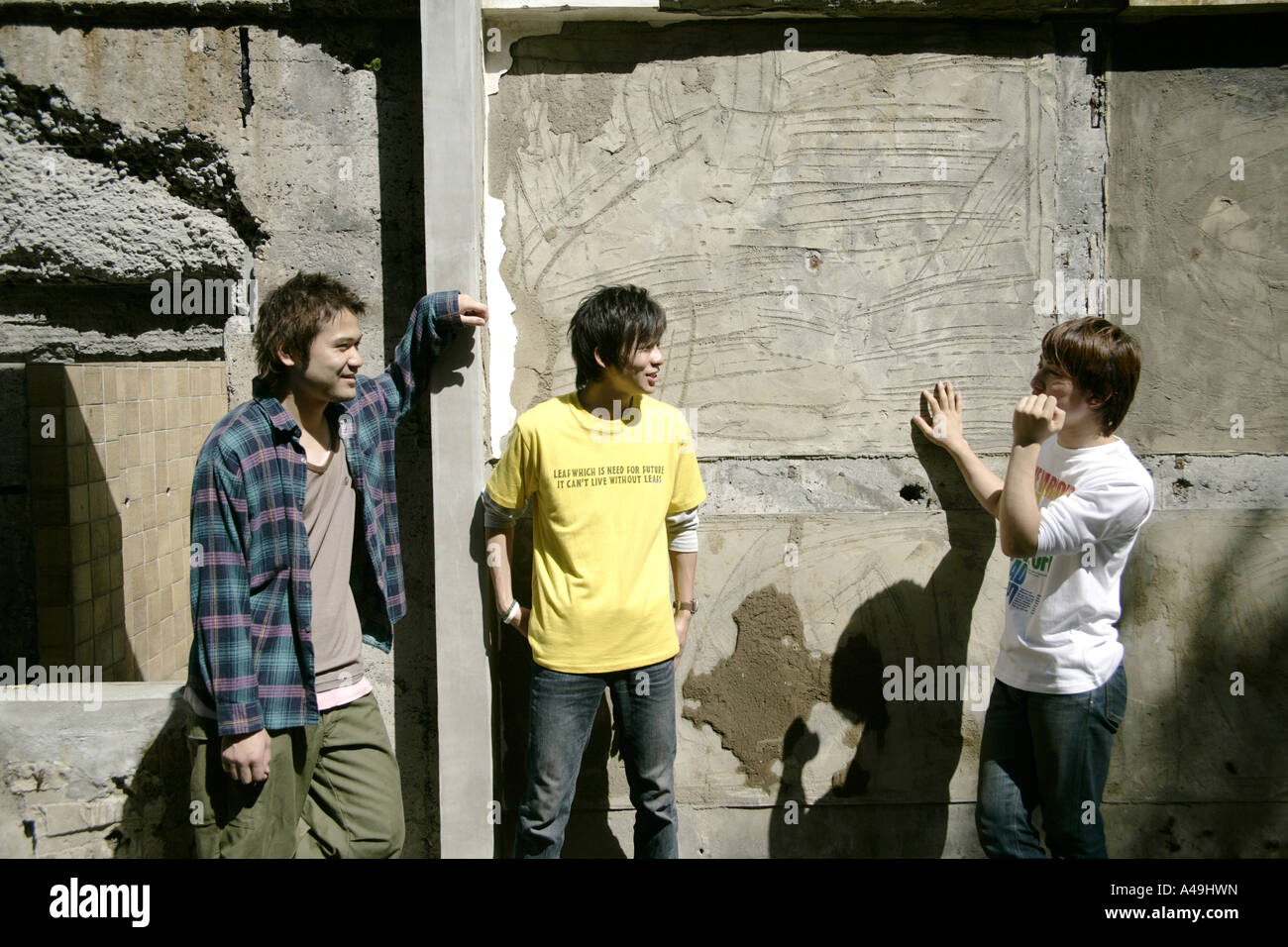 Three young men standing in front of wall Stock Photo - Alamy