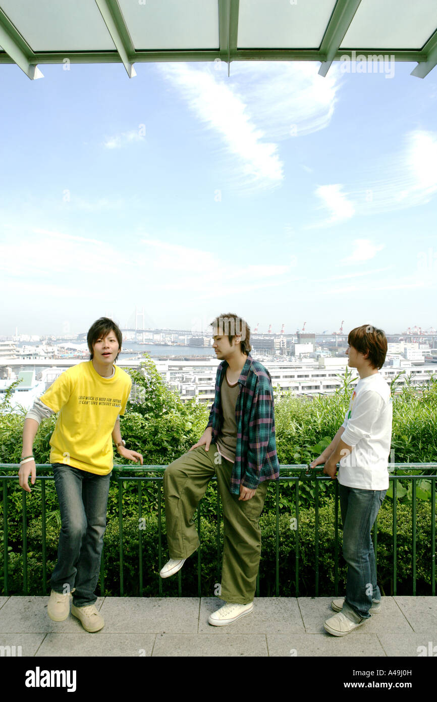 Three young men standing beside a railing Stock Photo - Alamy