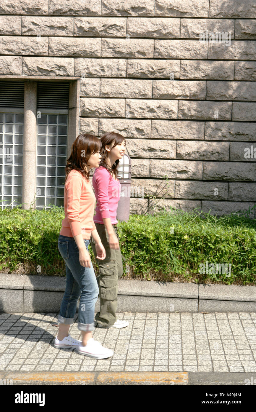 Side profile of two young women walking on a footpath Stock Photo - Alamy