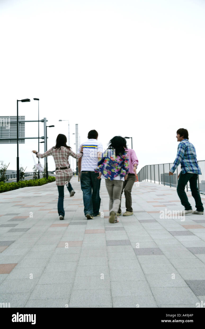 Three young men and two young women walking on the road Stock Photo - Alamy