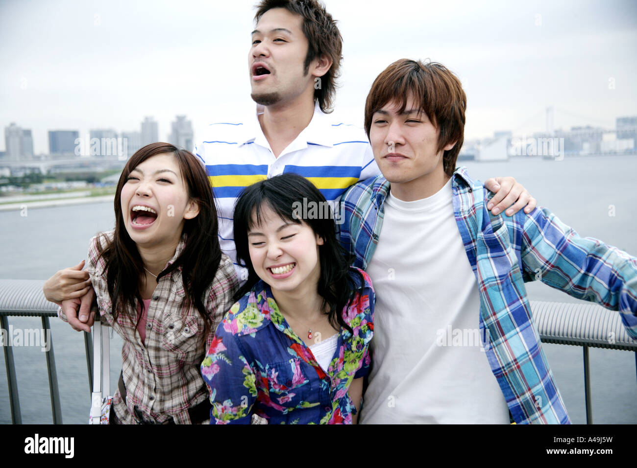 Two young women and two young men leaning against a railing Stock Photo ...