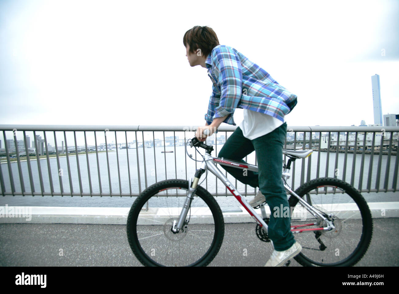 Side profile of a young man riding a bicycle Stock Photo - Alamy