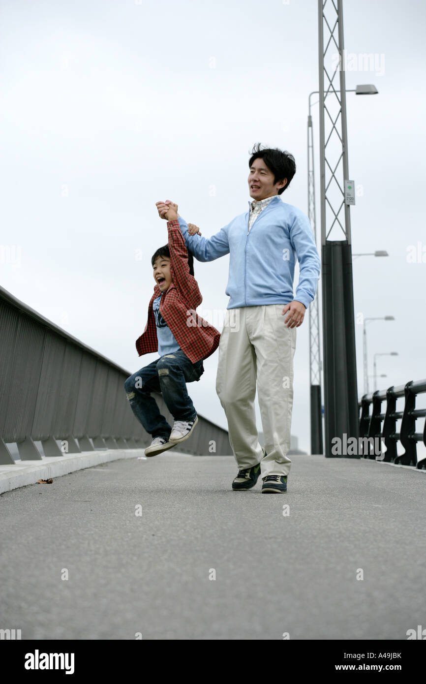Mid adult man lifting his son and holding his hand Stock Photo - Alamy