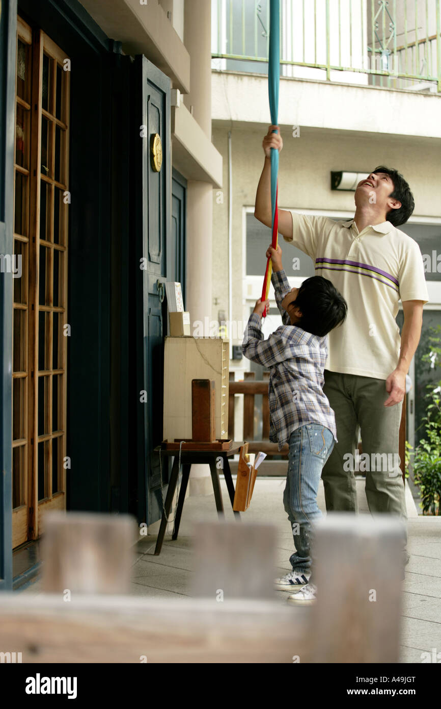 Mid adult man and his son ringing a bell at a monastery Stock Photo - Alamy