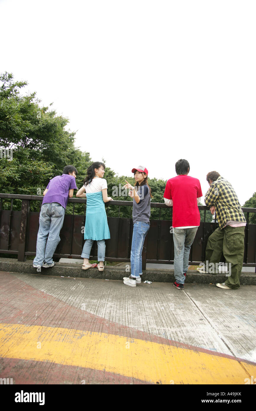 Three young women and two young men leaning against a railing Stock ...