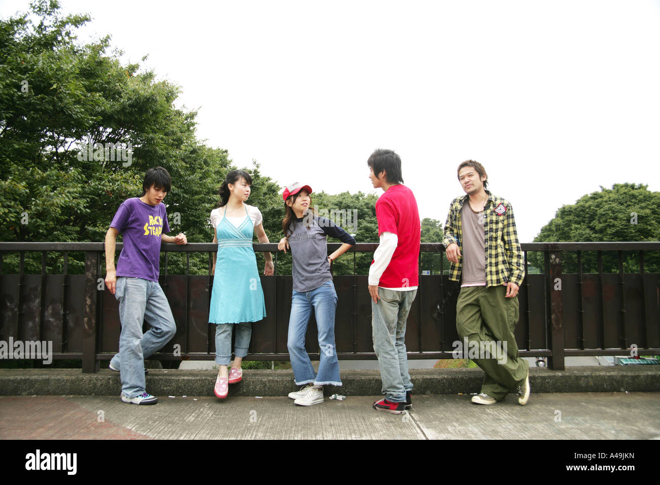 Three young women and two young men leaning against a railing Stock ...