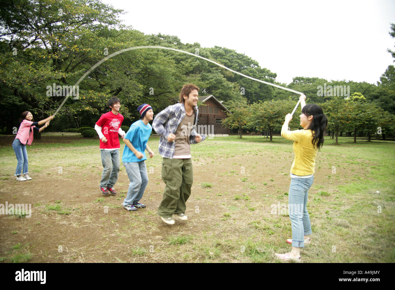 Three young men and two young women playing jump rope Stock Photo - Alamy