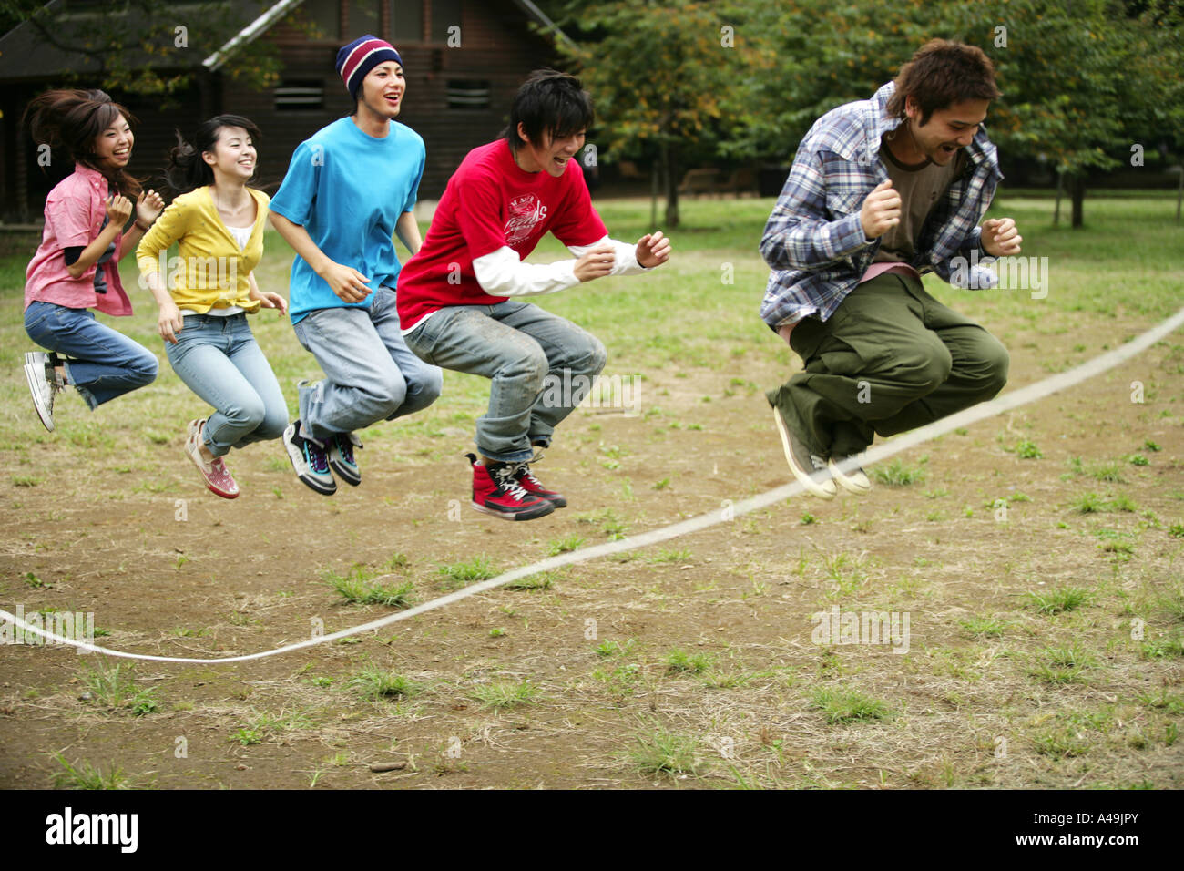 Three young men and two young women playing jump rope Stock Photo - Alamy