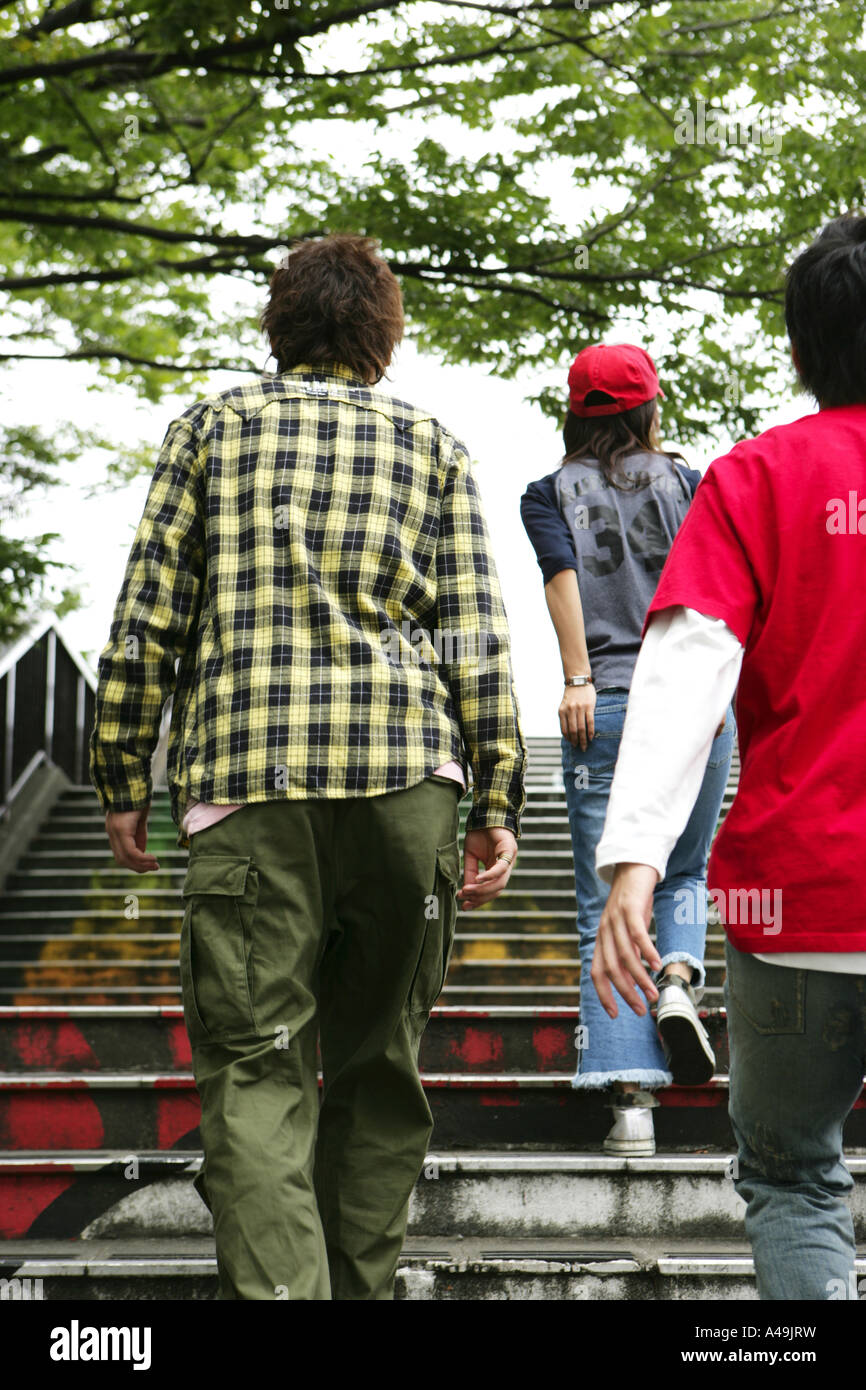 Rear view of two men and a woman walking up steps Stock Photo - Alamy