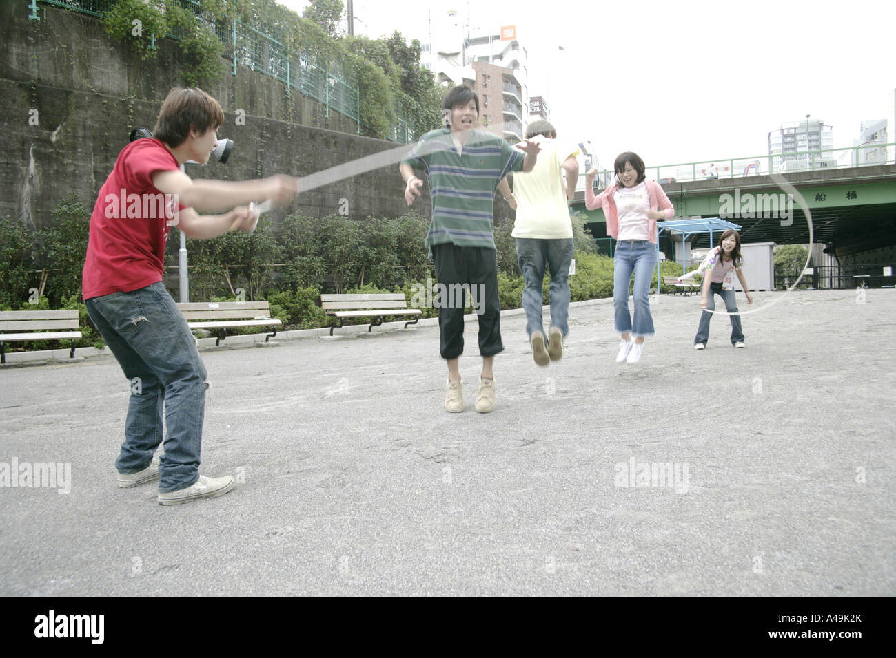 Three young men and two young women playing jump rope Stock Photo - Alamy