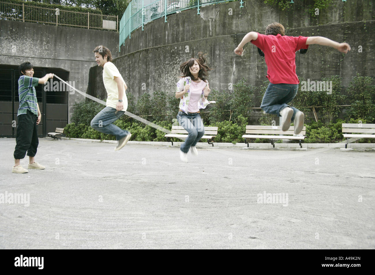 Three young men and a young woman playing jump rope Stock Photo - Alamy