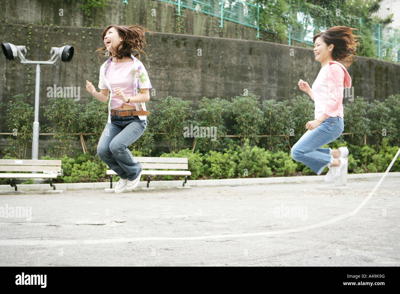 Side profile of two young women jumping on a jump rope Stock Photo - Alamy