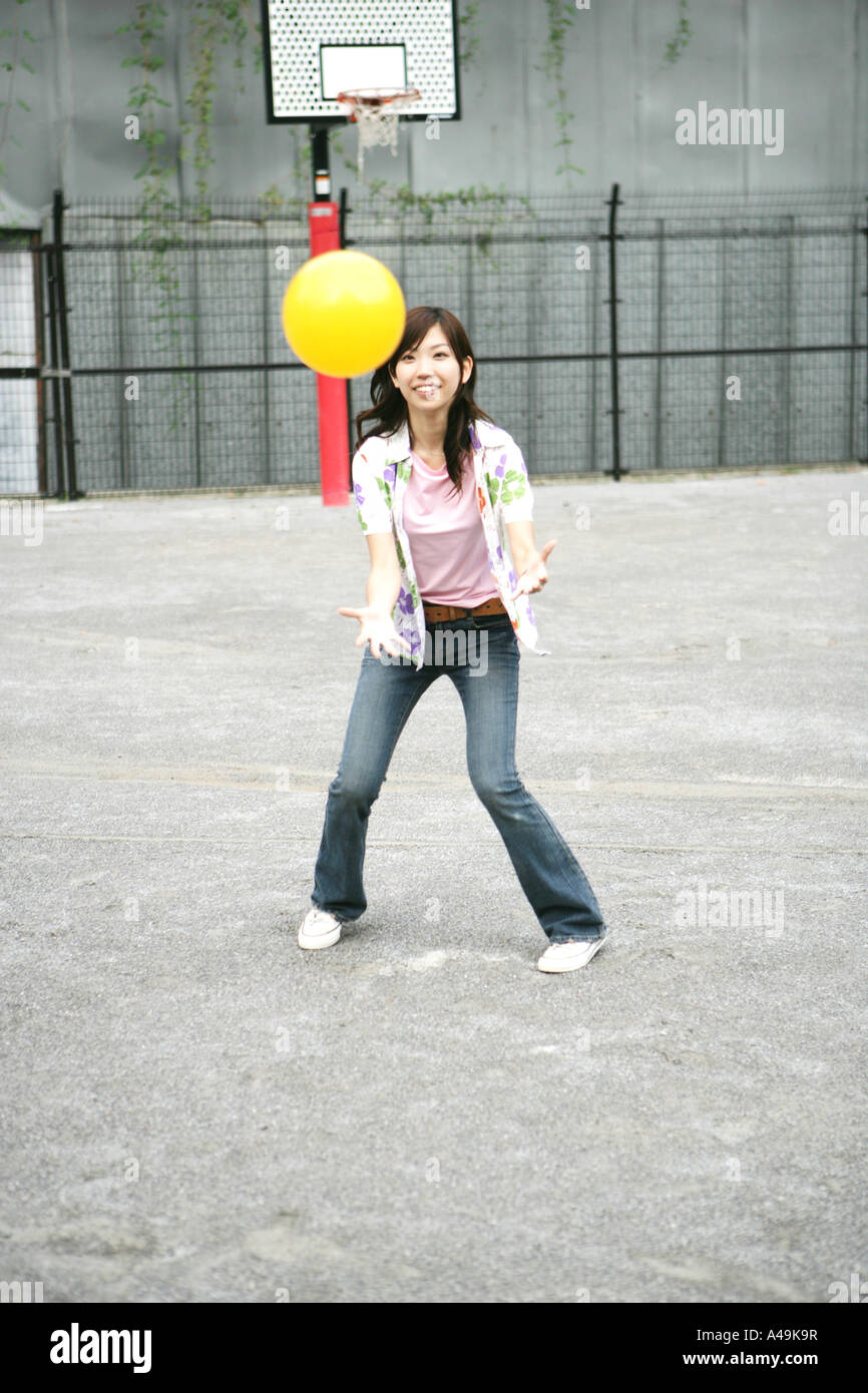 Young woman tossing a ball in air Stock Photo - Alamy
