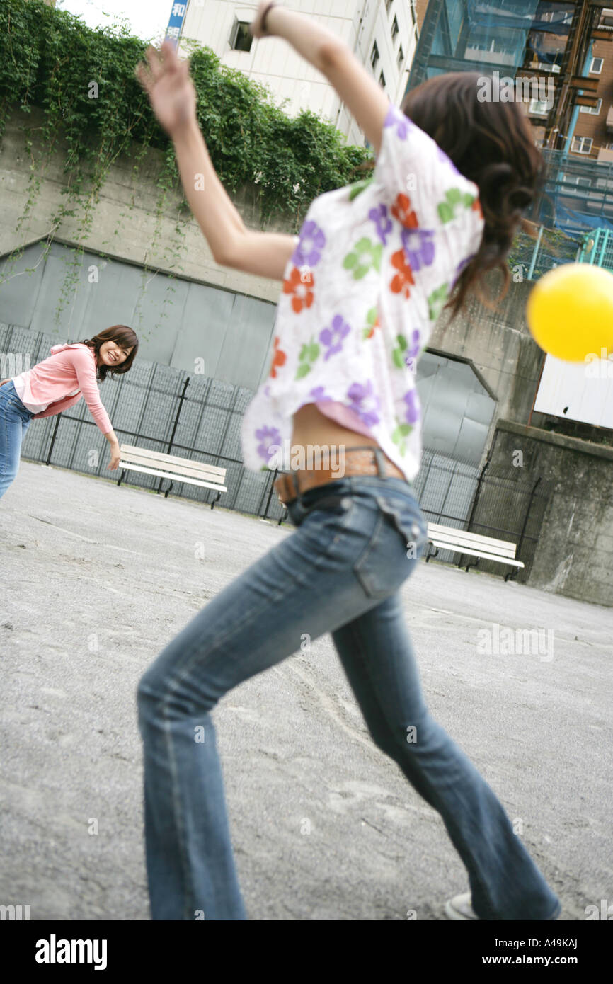 Side profile of a young woman throwing a ball at another woman Stock ...