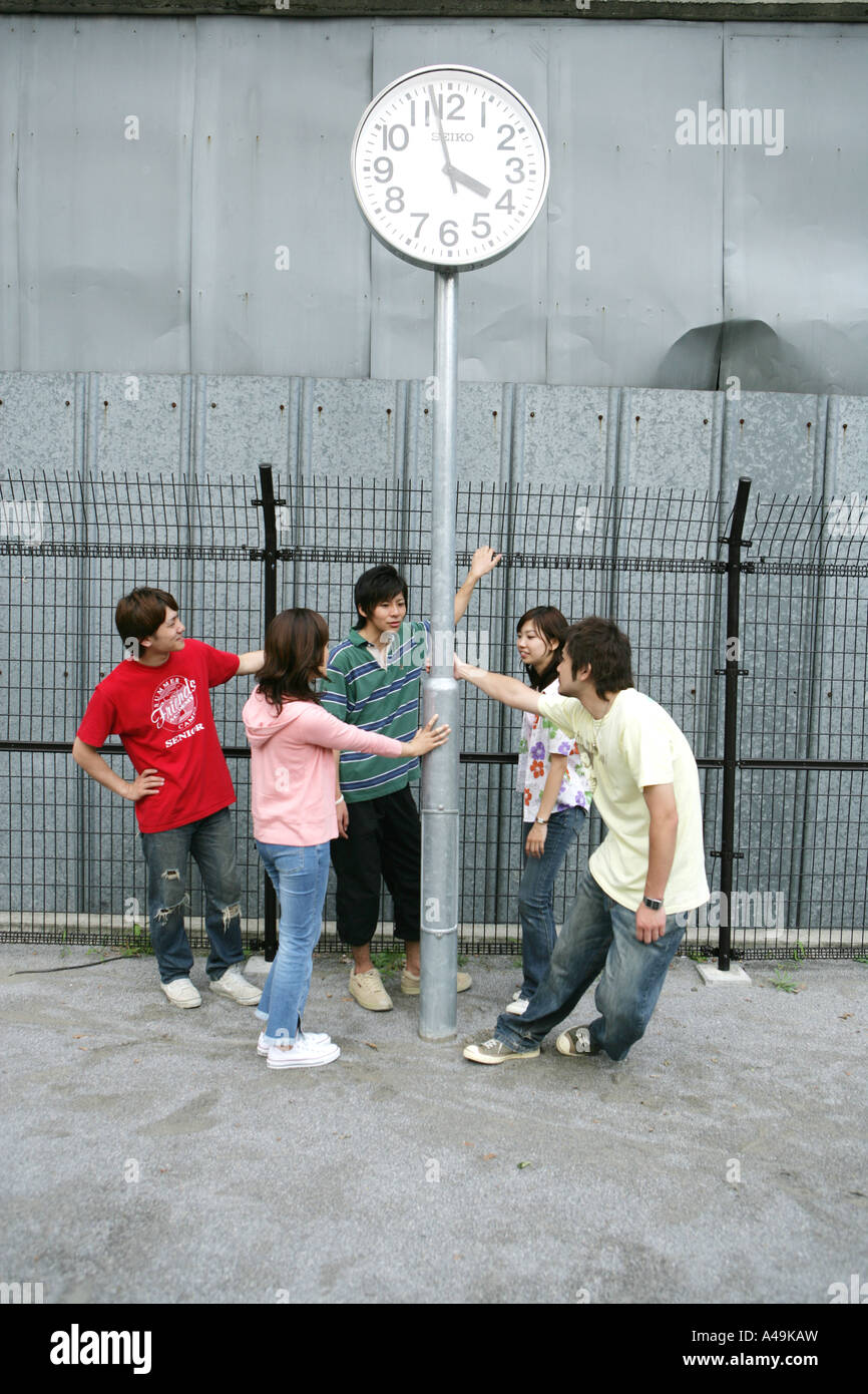 Five friends standing around a pole with a clock Stock Photo - Alamy