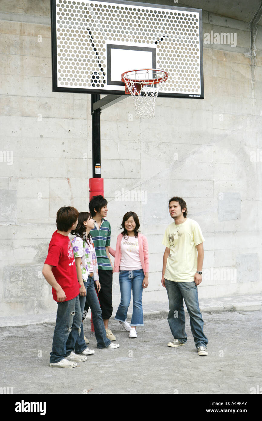Five friends standing under a basketball hoop Stock Photo - Alamy