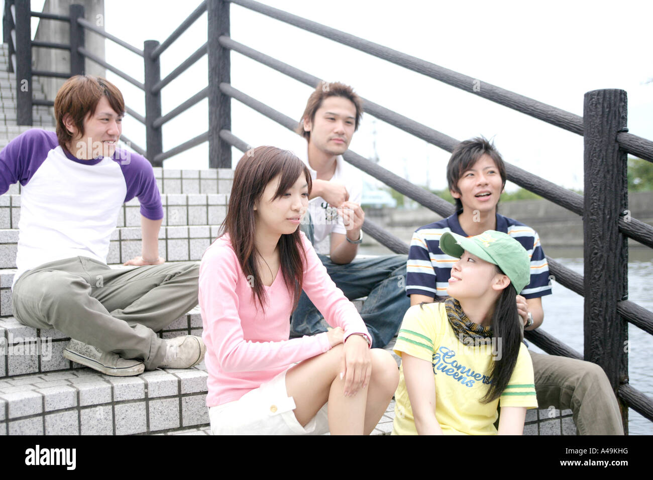 Three young men and two young women sitting on steps Stock Photo - Alamy