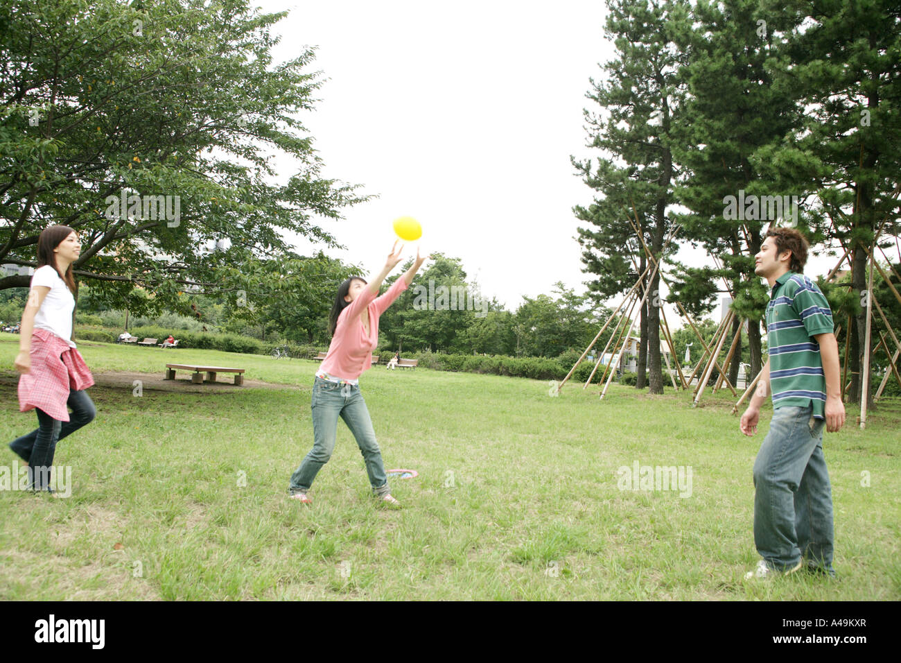 Young woman reaching for a ball with her two friends looking at her ...