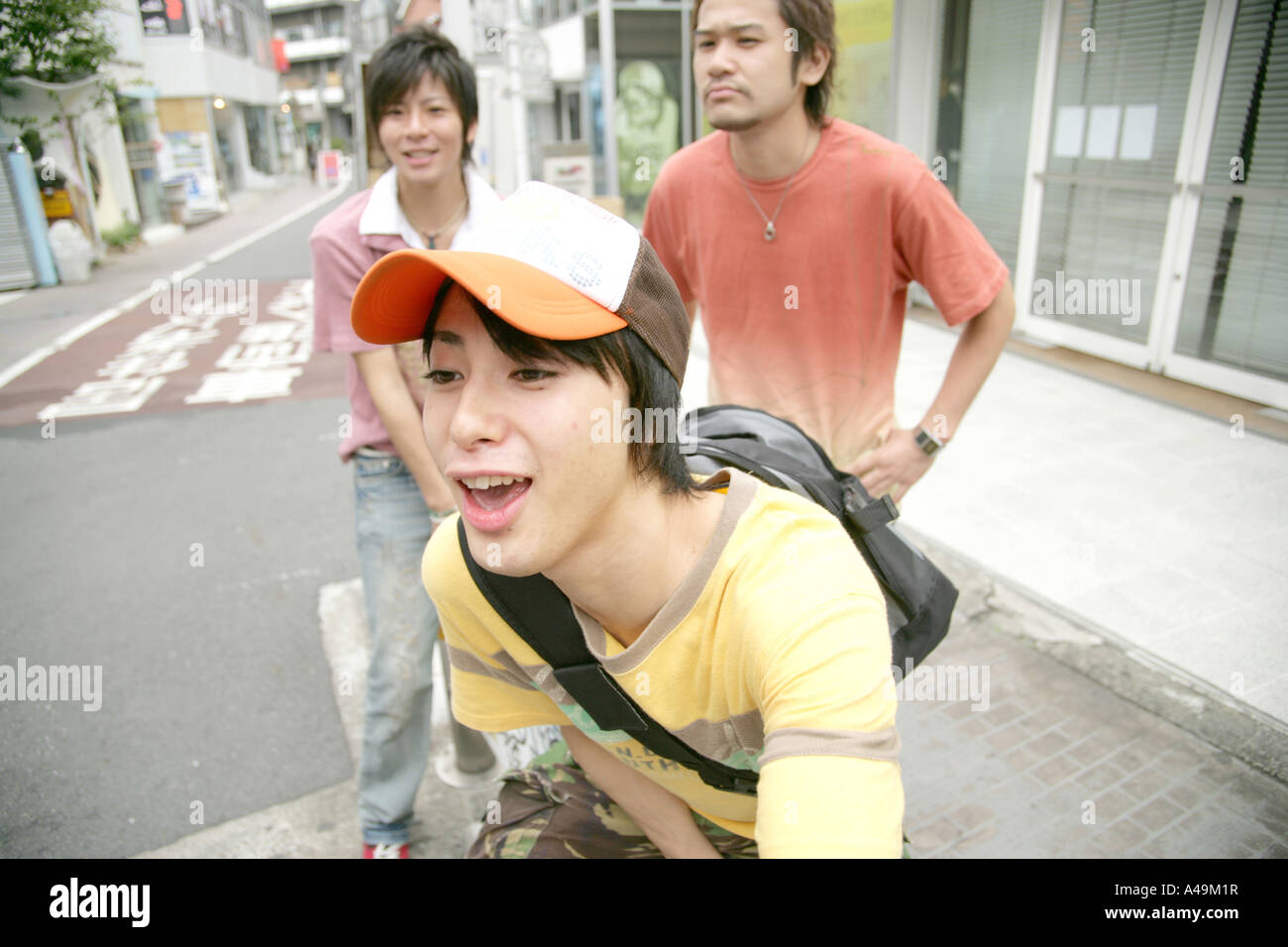 Close up of a young man smiling with two young men standing behind him ...
