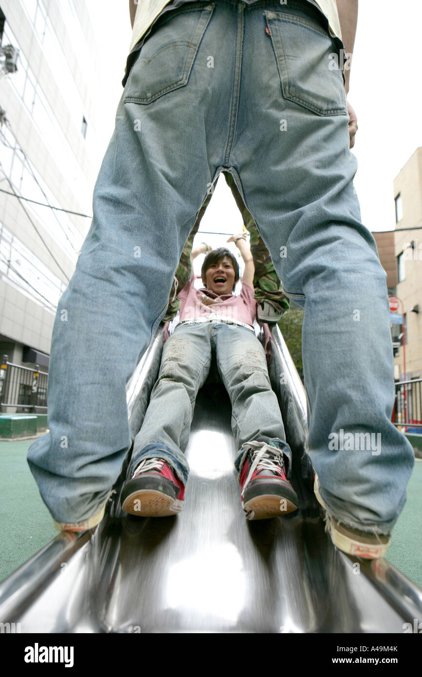 Low section view of two people standing over a young man on a slide ...
