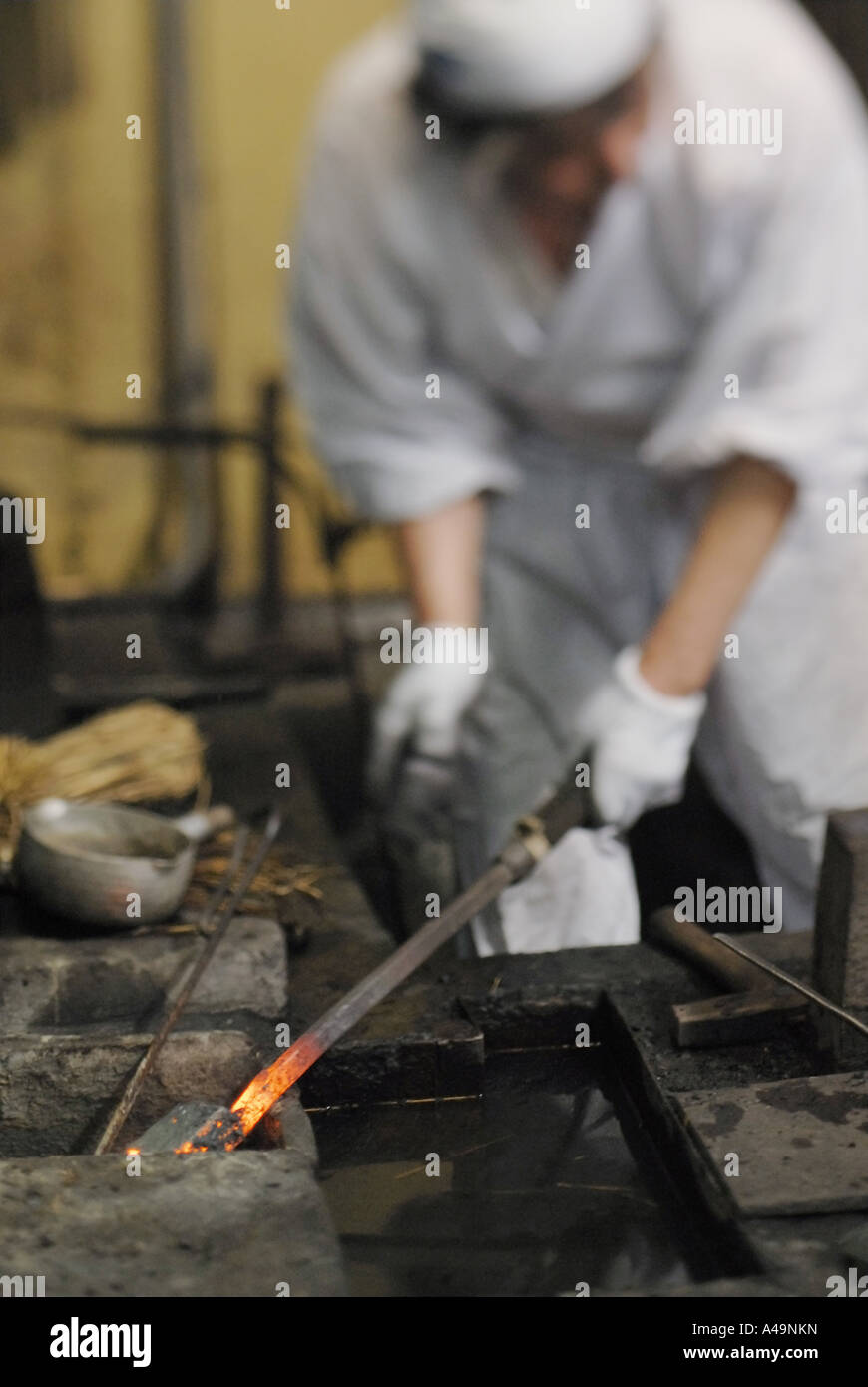 Blacksmith holding a heated metal rod Stock Photo - Alamy