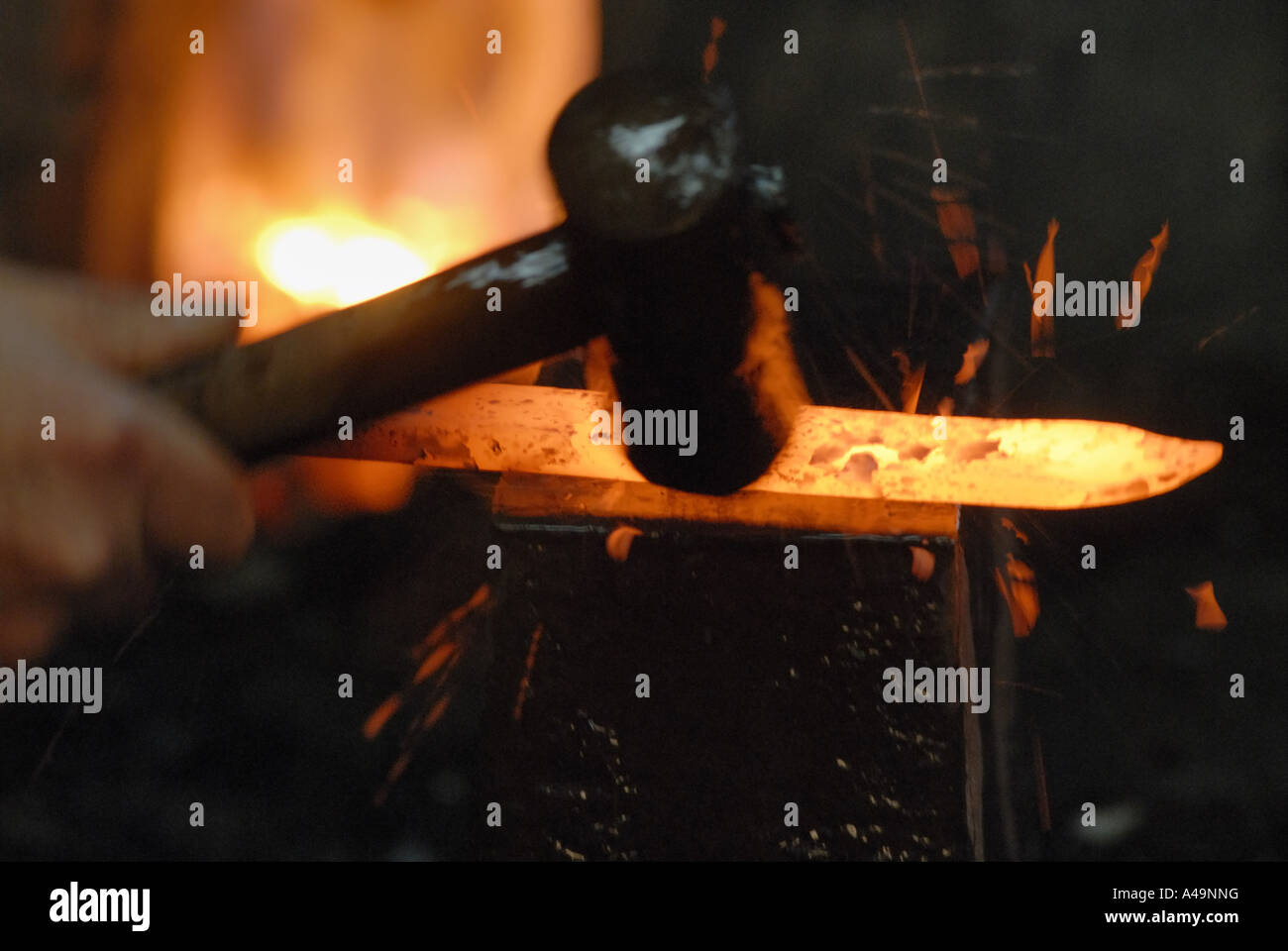 Close up of a blacksmith s hand hitting a heated metal rod with a ...