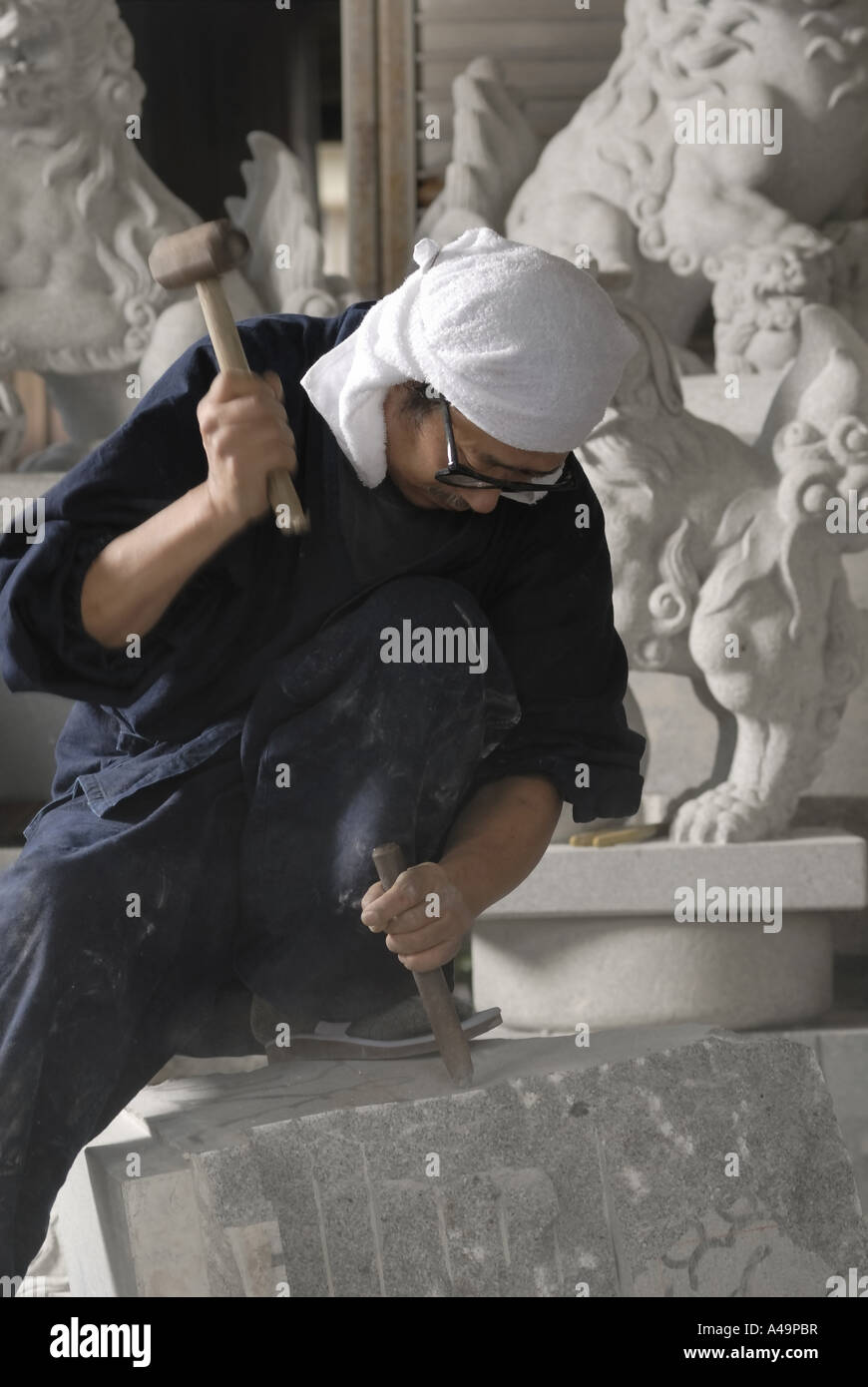 Sculptor carving a stone with a chisel and a hammer Stock Photo - Alamy