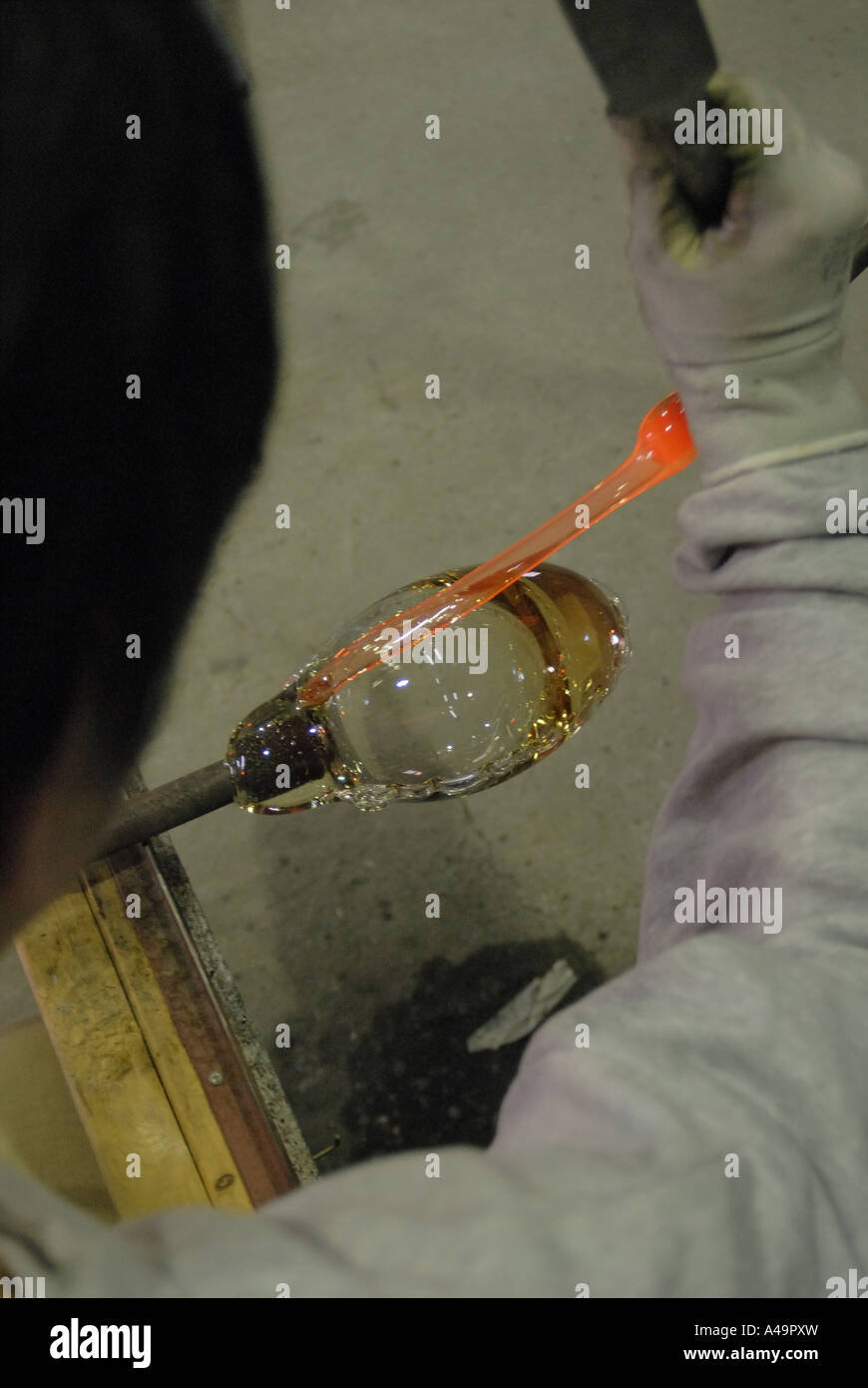 High angle view of a person blowing molten glass with a blow pipe Stock ...