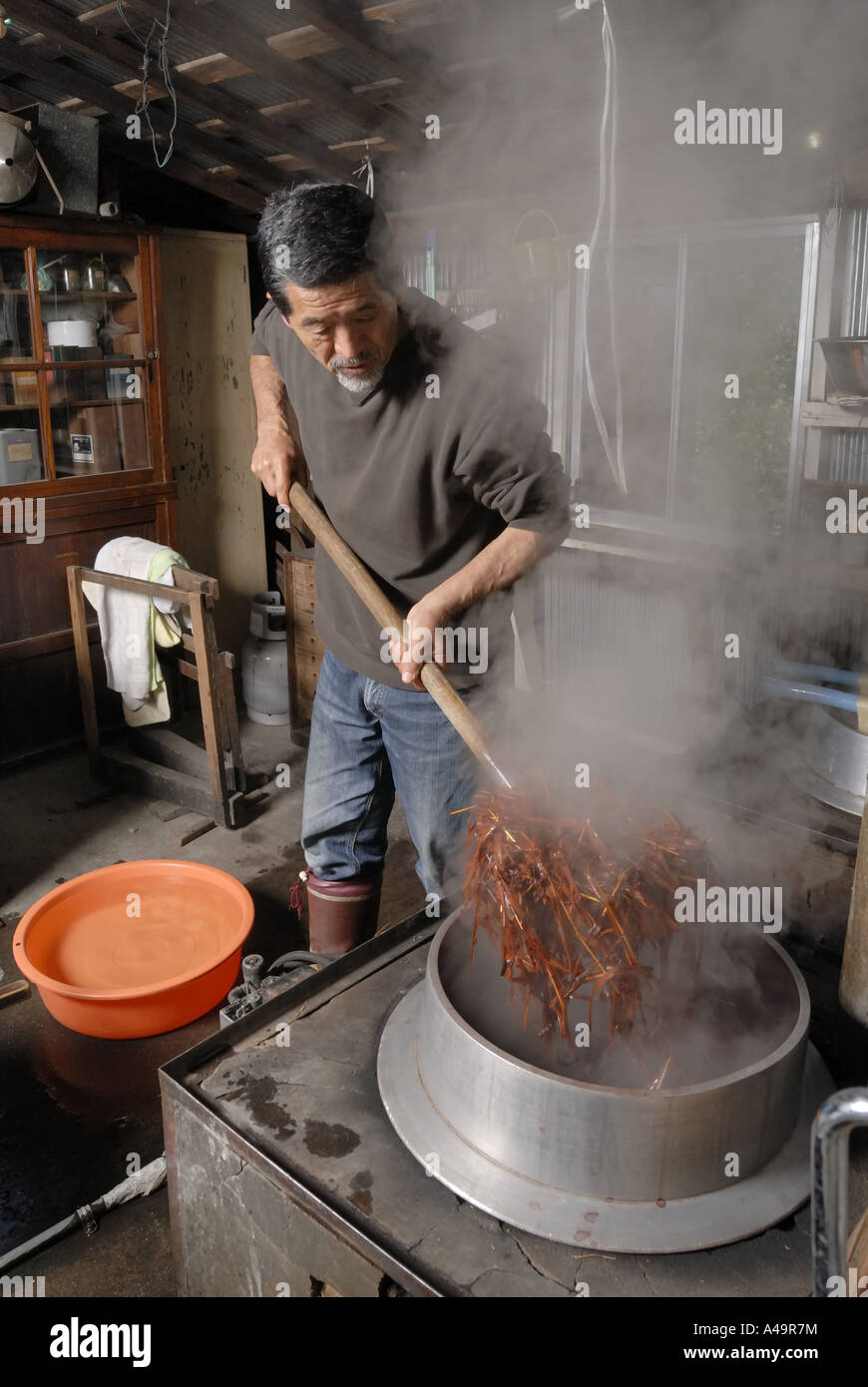 Mature man boiling dye in a container Stock Photo - Alamy