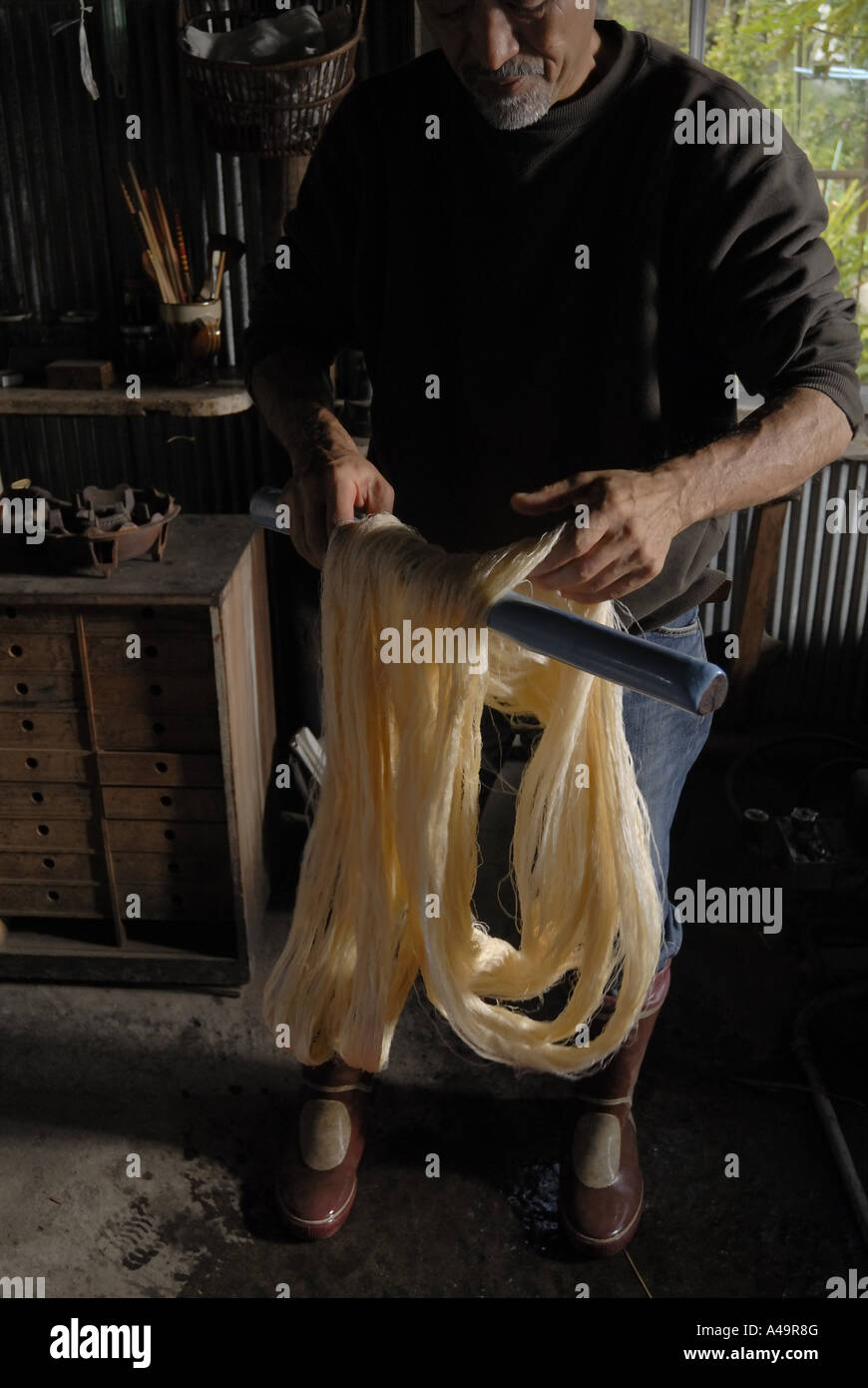 Mature man arranging silk threads on a wooden stick Stock Photo - Alamy