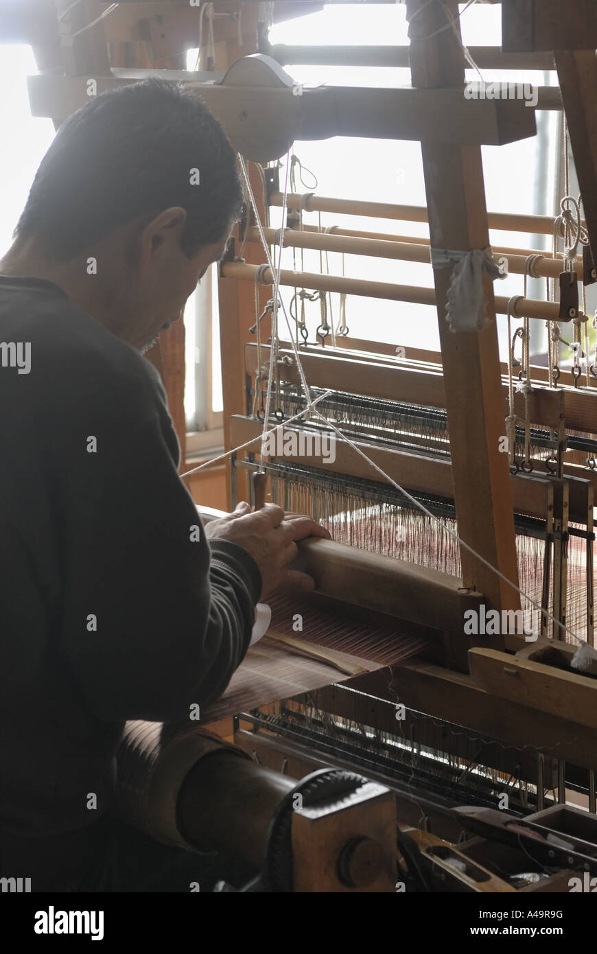 Side profile of a mature man working on a loom Stock Photo - Alamy